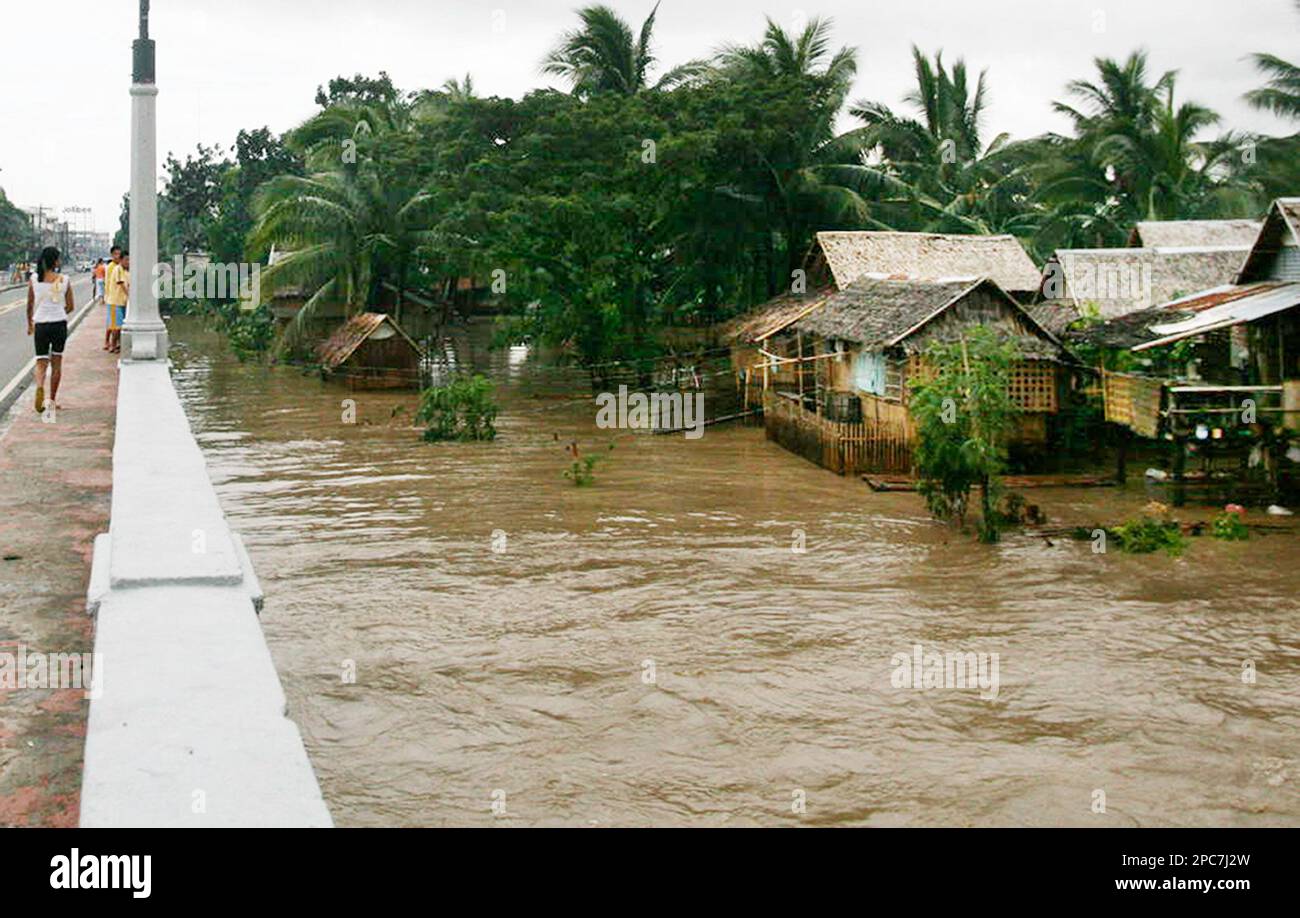 Residents look at submerged houses along a flooded bridge in Kalibo ...