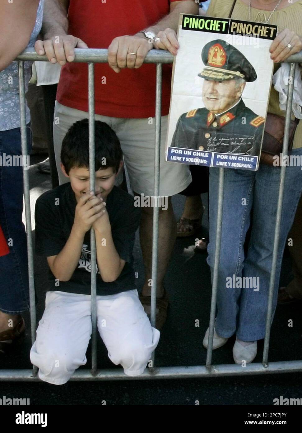 A boy kneels as supporters of former Gen. Augusto Pinochet stand ...