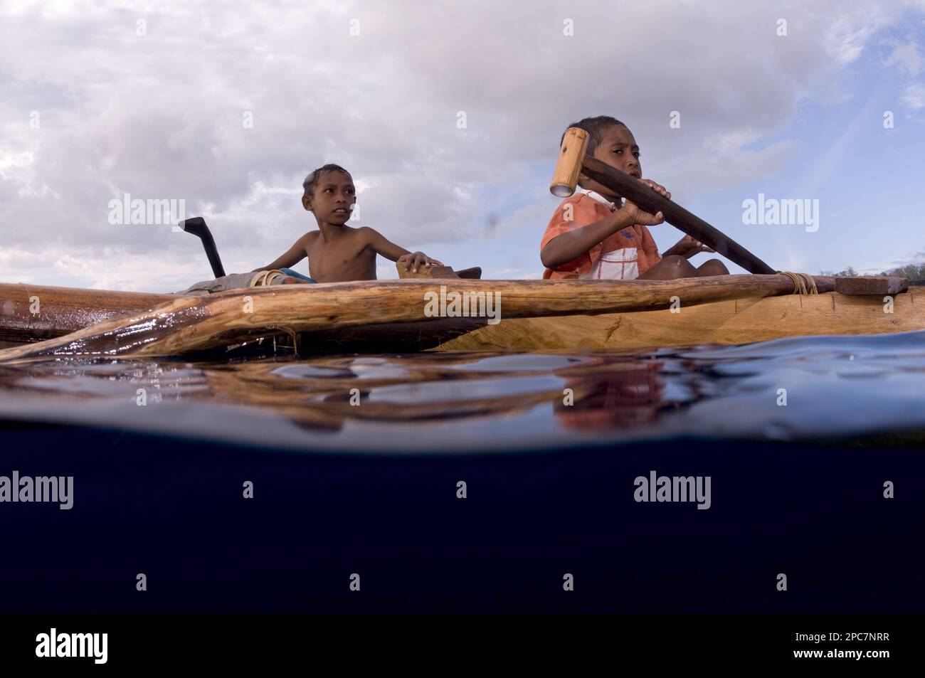 Boys rowing a canoe at sea, near Perai village, West Wetar Island, Alor ...