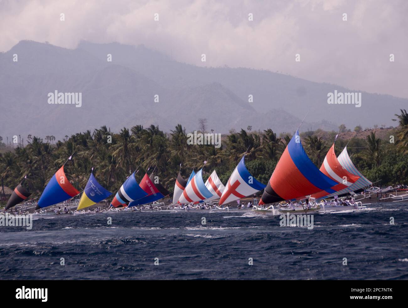 Boats with colourful sails during the Jukung Race, with mountains in ...