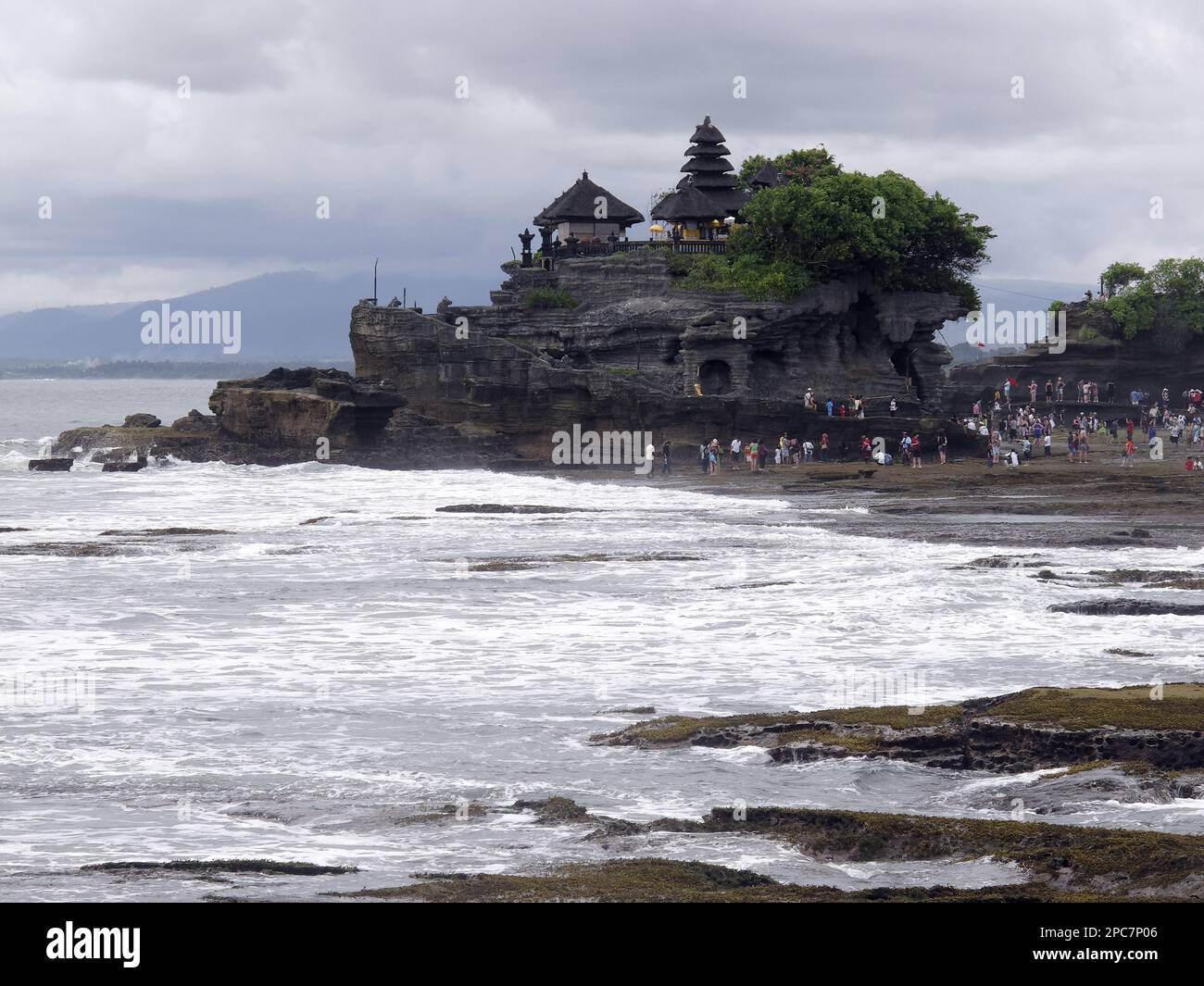 View from tourists in the temple on a rock formation on the coast, Pura ...