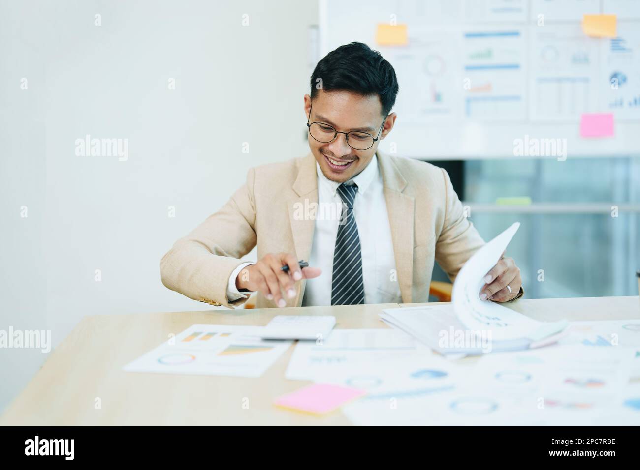 Portrait of an Asian male accountant working on a desk calculating ...