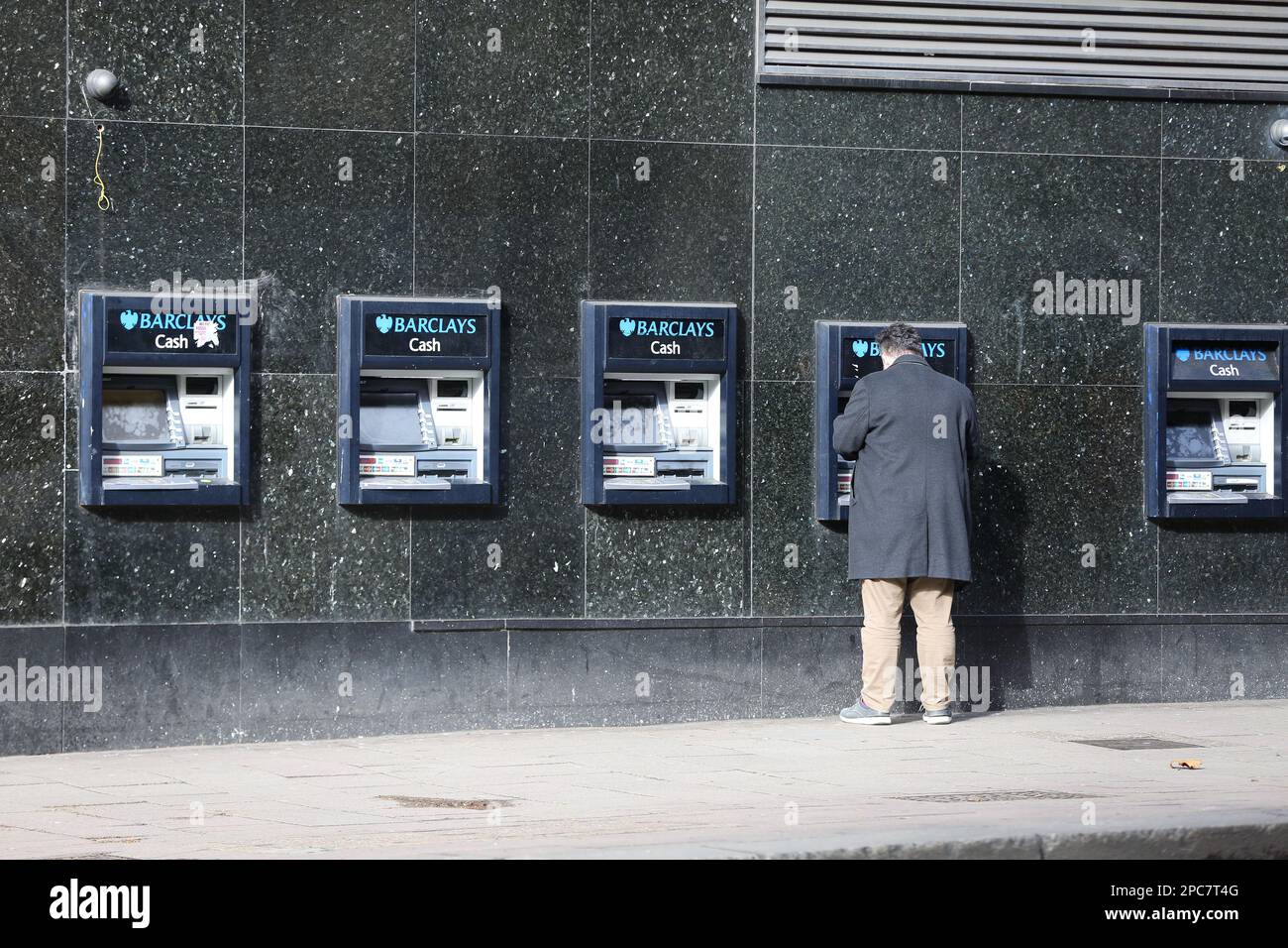 A man uses a cash point machine outside a branch of Barclays Bank in ...