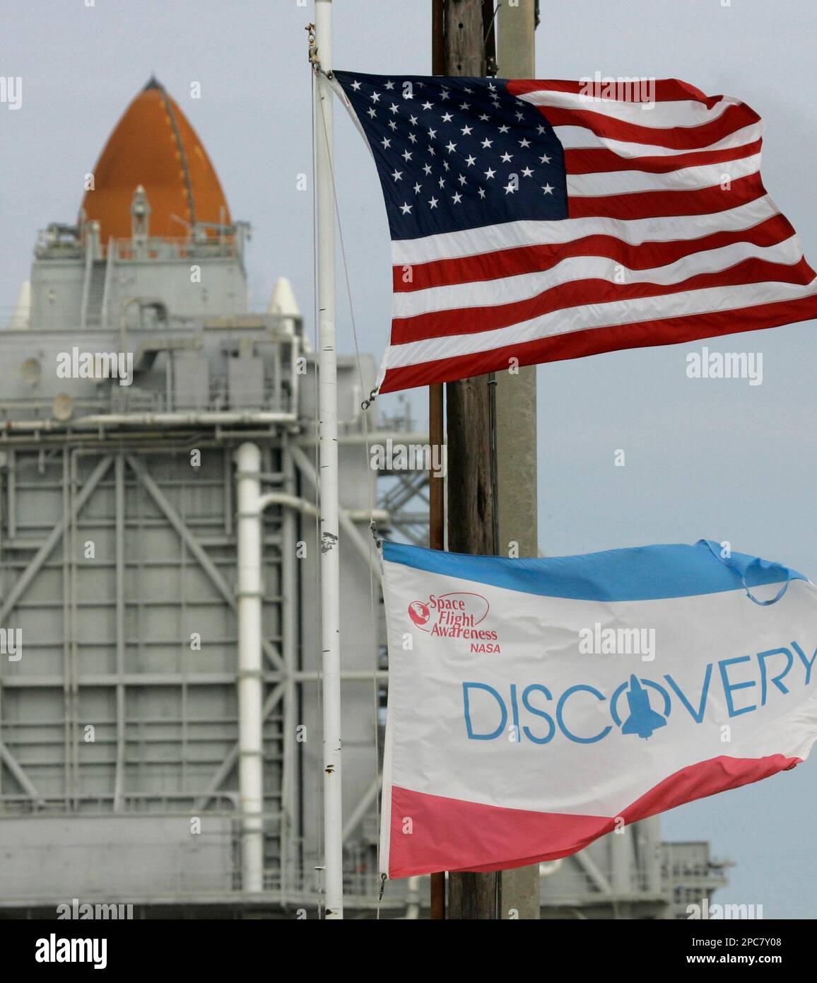 The American flag and the Discovery mission flag blow briskly in the ...