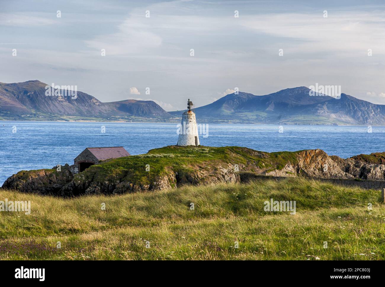 View of lighthouse and coastline on tidal island, Llanddwyn Island ...