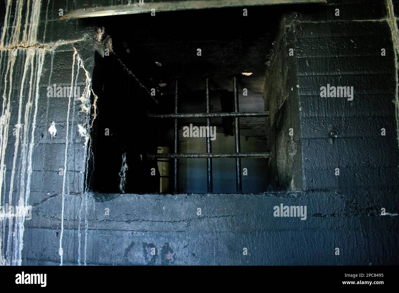 An opening in a black brick wall. The opening is crossed with dark ...