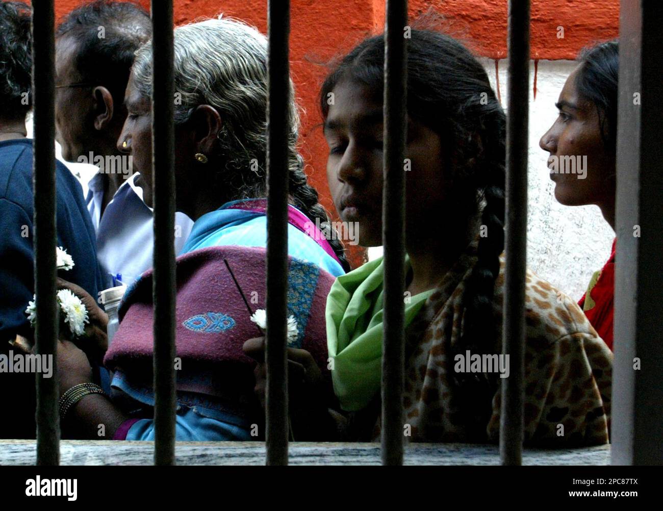 A low-caste Hindu holds flowers in her folded hands as she stands ...