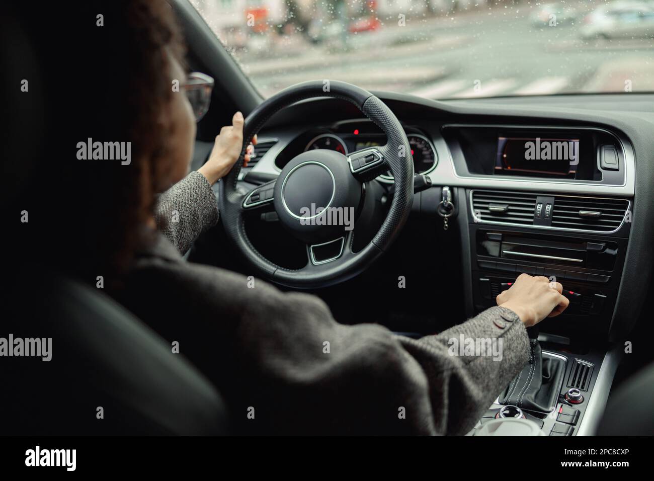 SIde view of businesswoman driving car with one hand on steering wheel ...