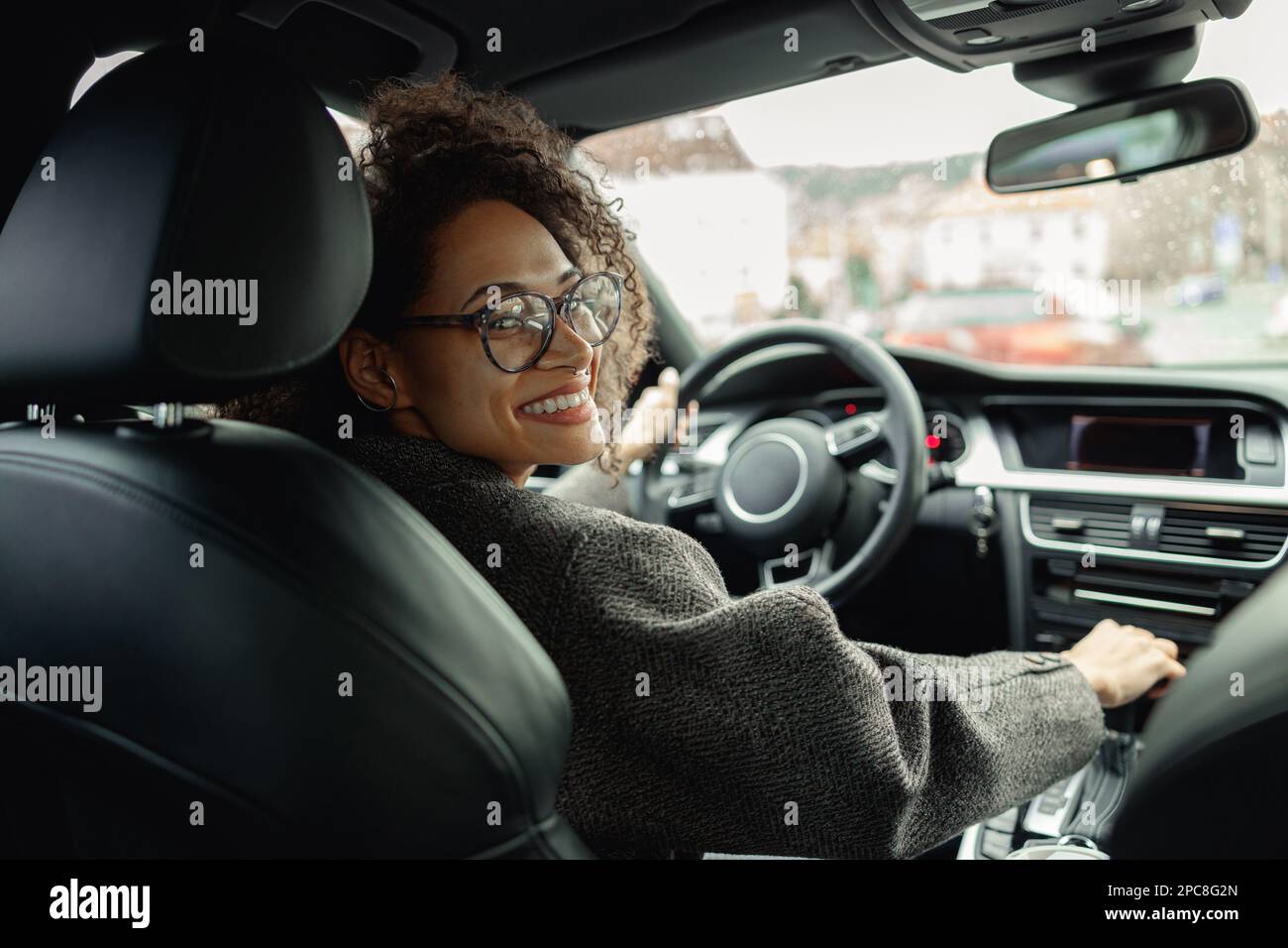 Woman driving car with one hand on steering wheel and another on gear ...