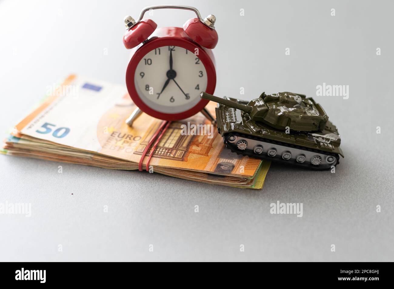 plastic model toy tanks on a pile of euro banknotes against wooden ...