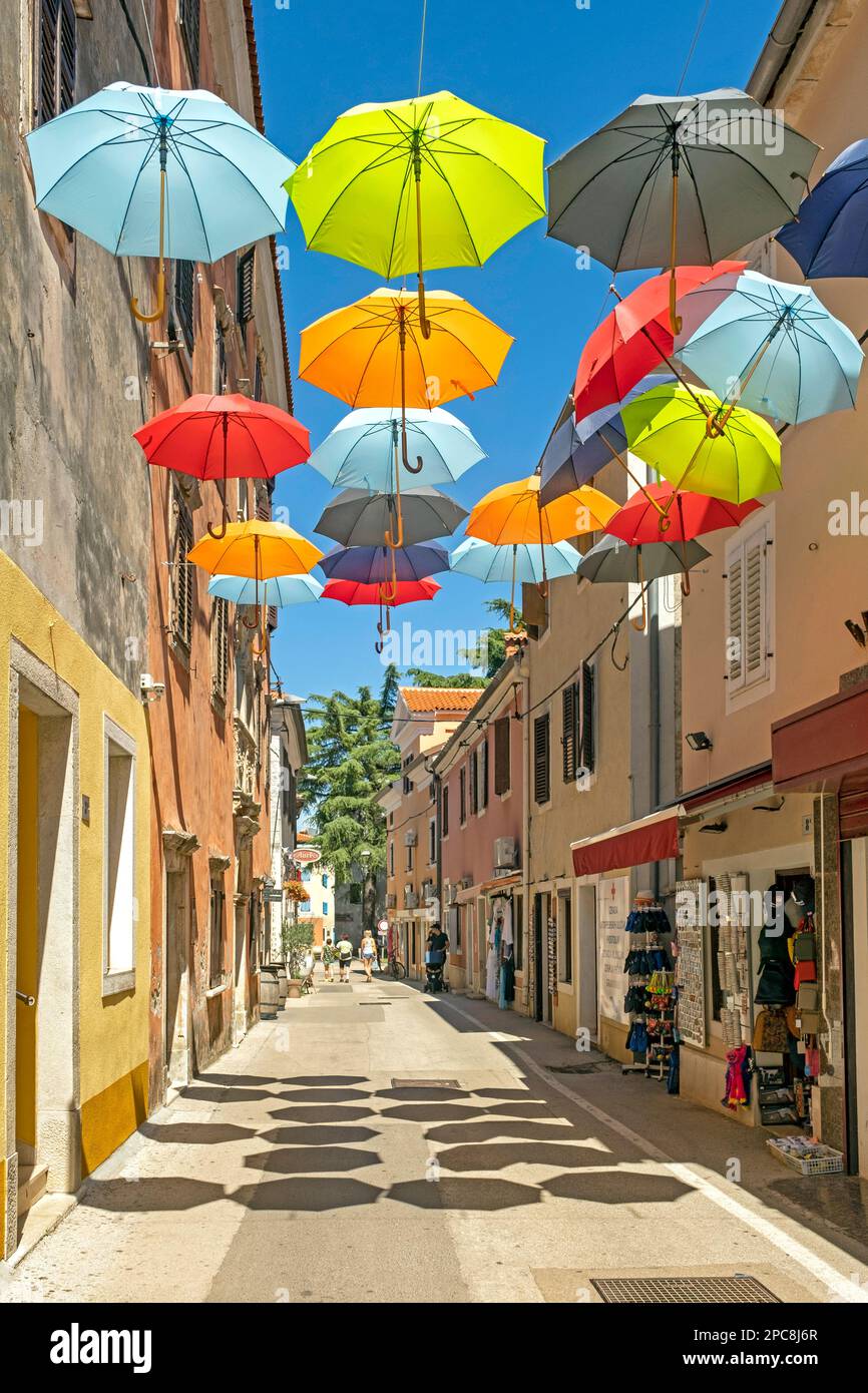Street with souvenir shops and colourful umbrellas in the historic town ...