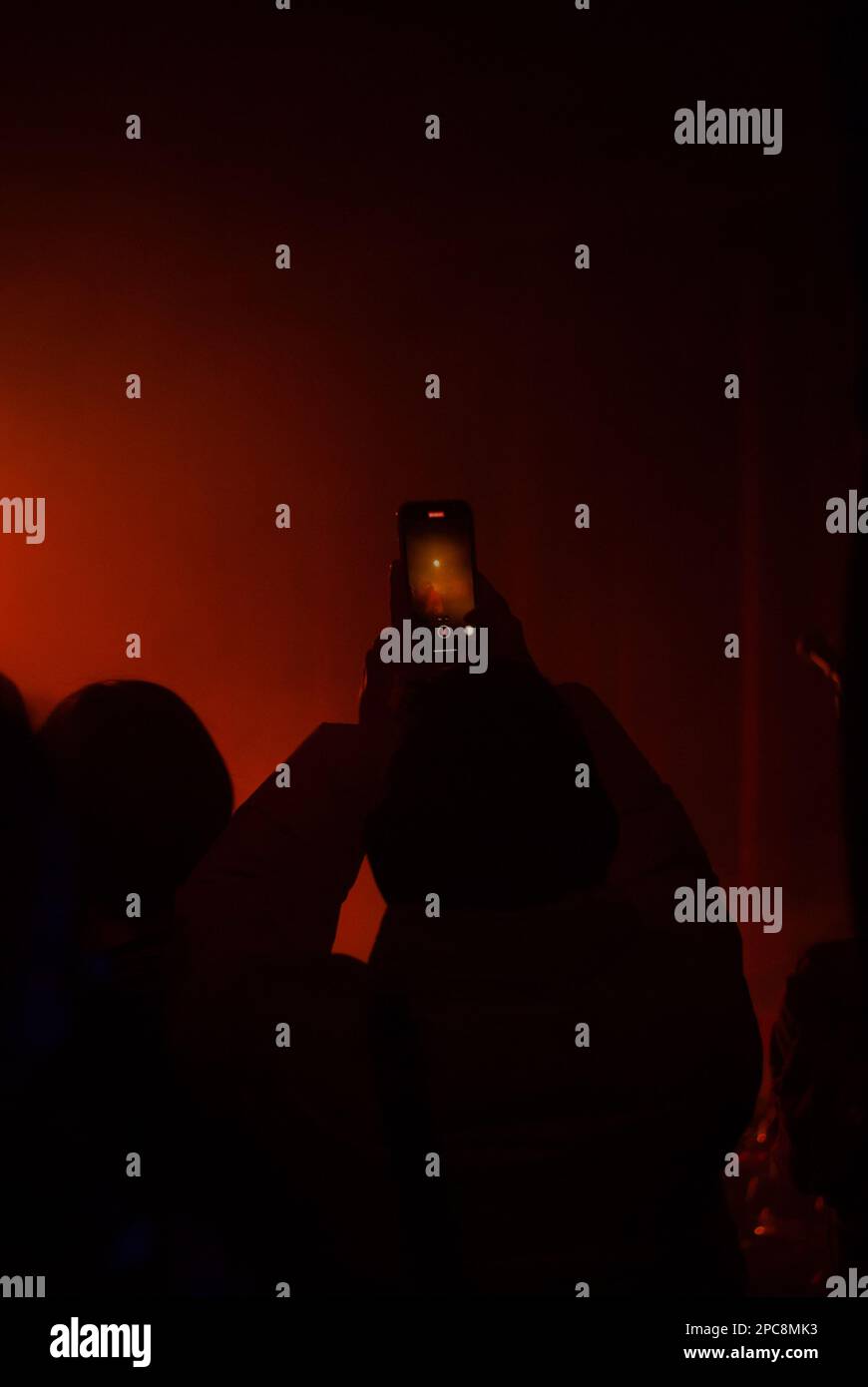 View on girl with phone in crowd in night club in red lights Stock ...