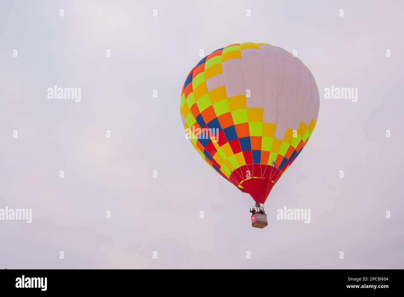 Colorful hot air balloon flying against grey winter sky at aerostat ...