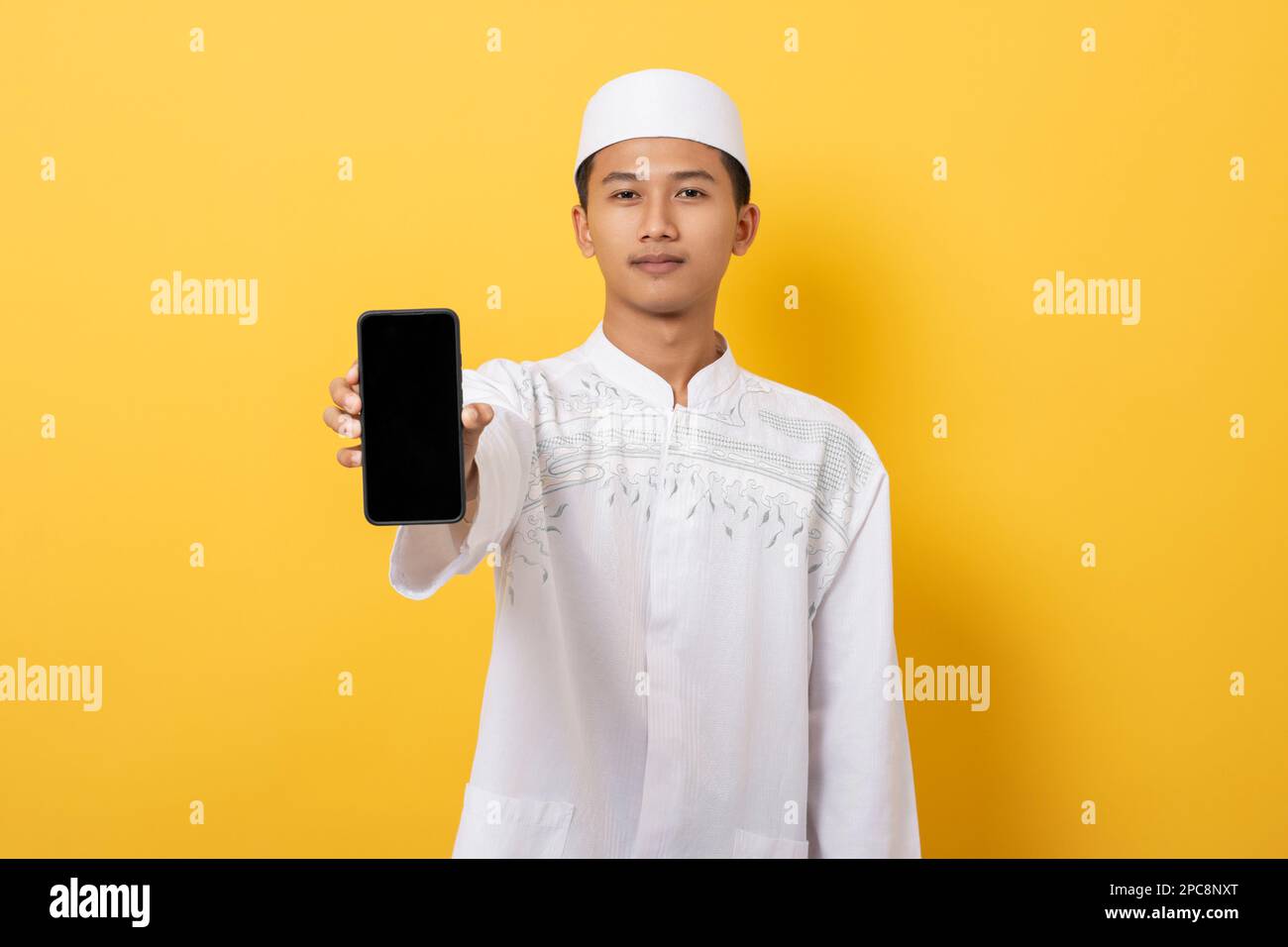 Young handsome asian muslim man holding and showing big smartphone with ...