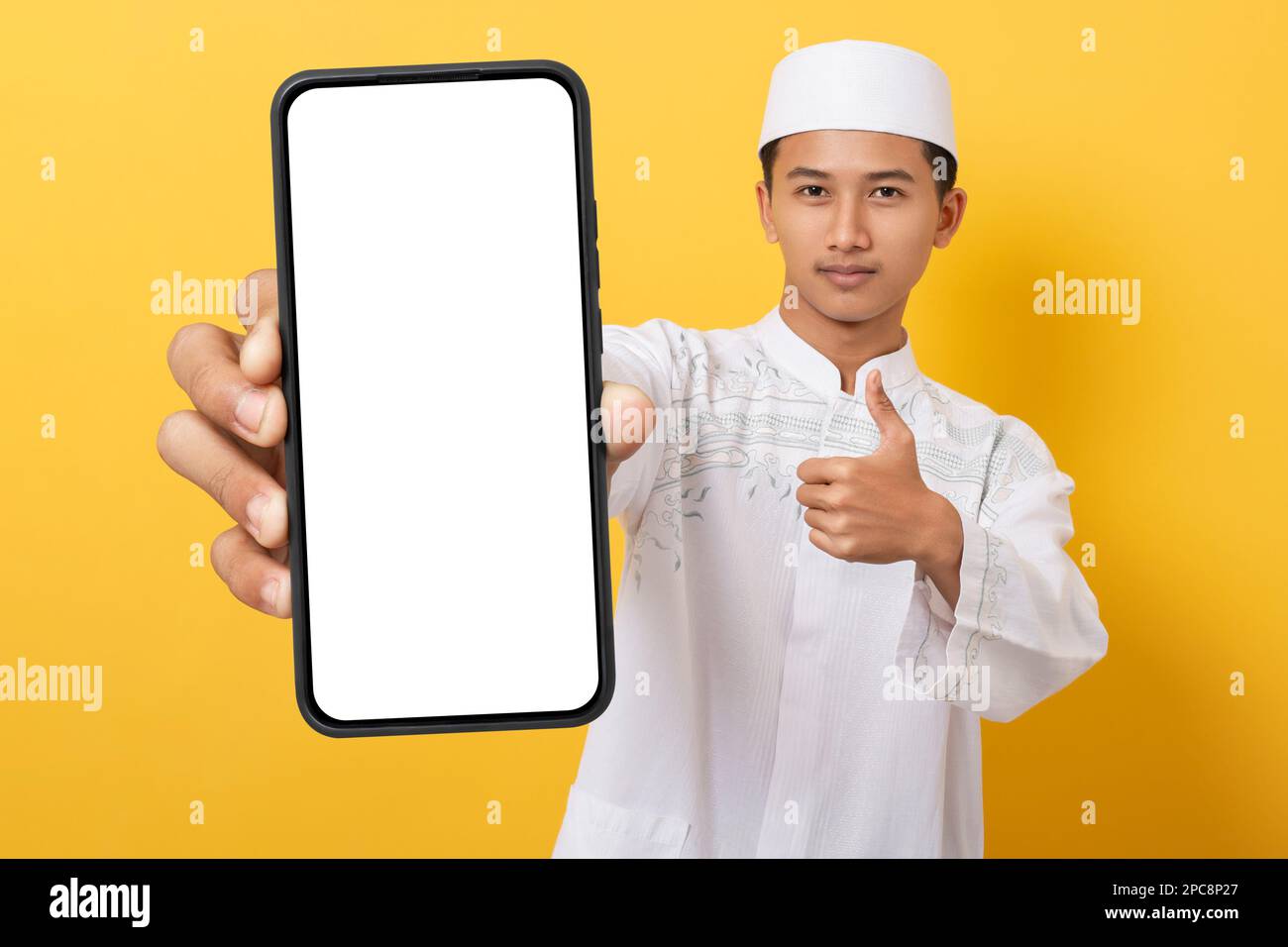 Young handsome asian muslim man holding and showing big smartphone with ...