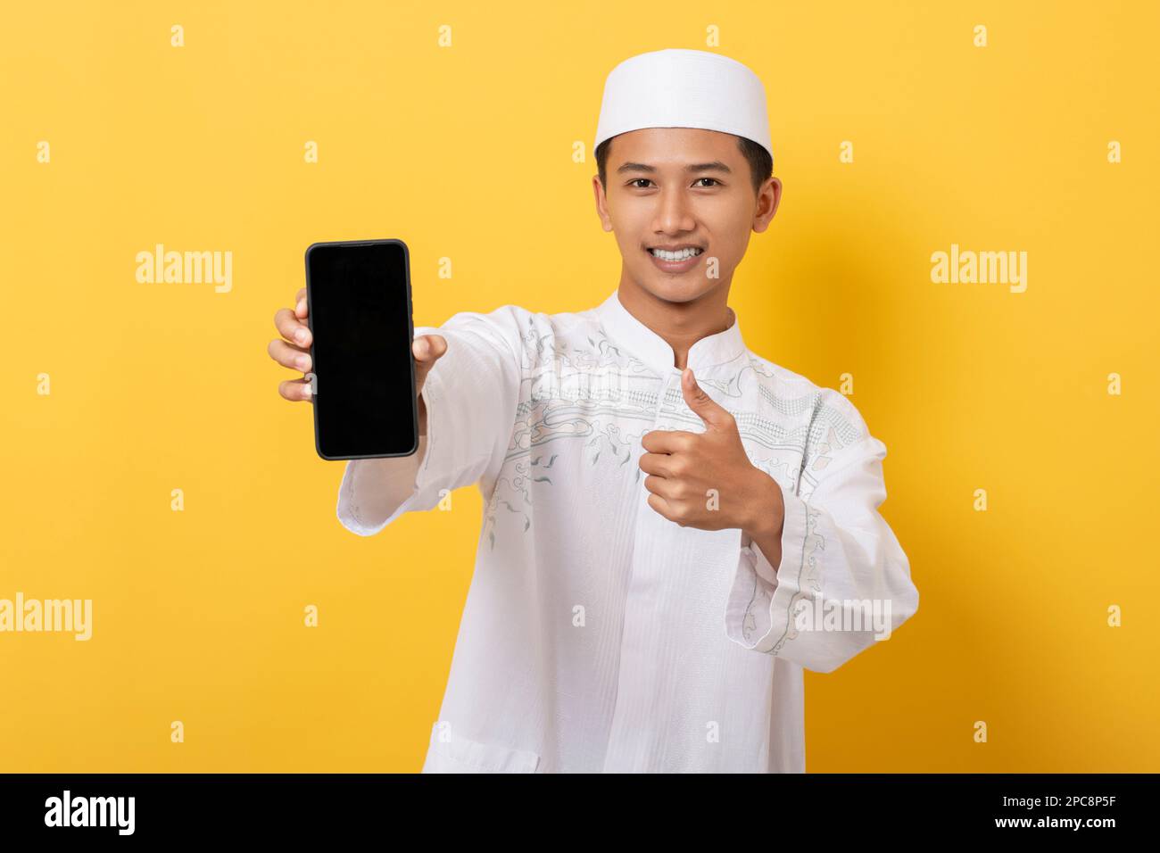 Young handsome asian muslim man holding and showing big smartphone with ...