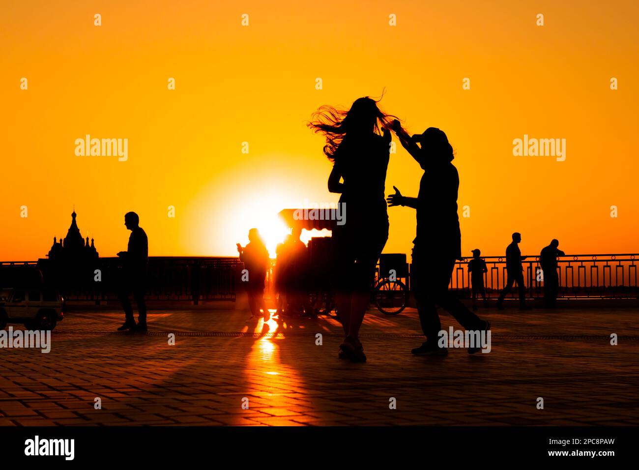 Woman and man couple silhouettes dancing against warm sunset orange sky ...