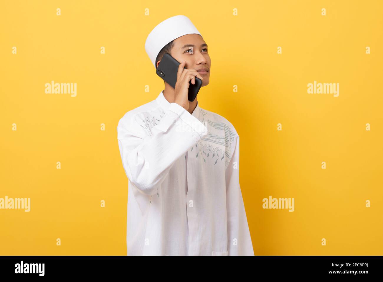 Young handsome asian muslim man standing over orange background talking ...