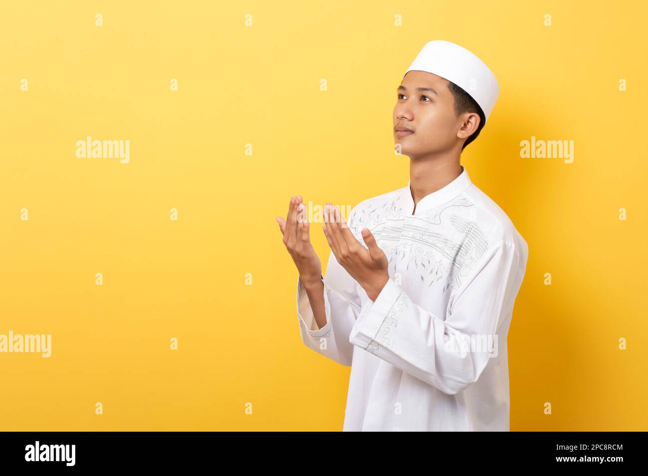 Young handsome asian religious muslim man praying isolated on orange ...