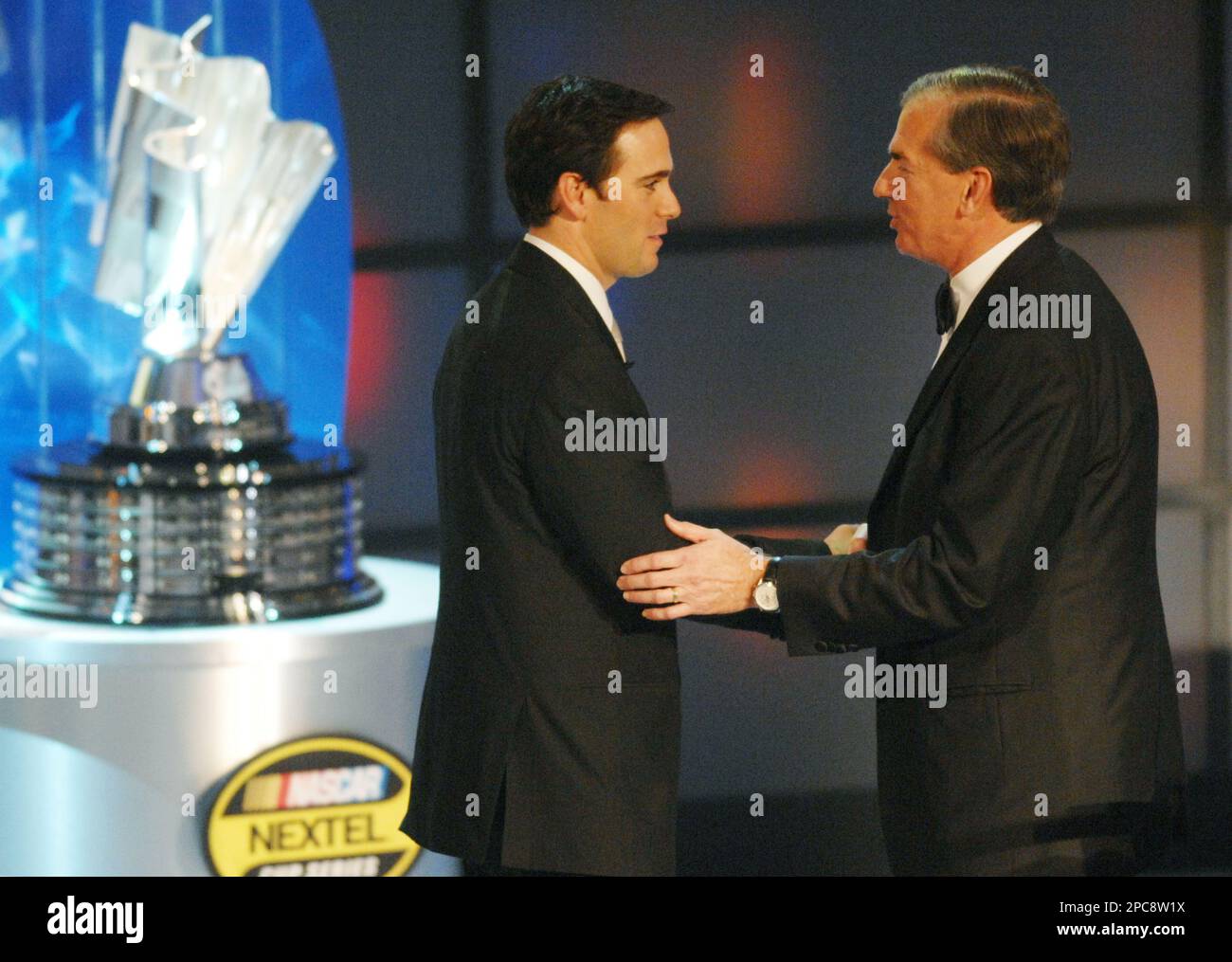 Jimmie Johnson, left, accepts the trophy for winning the NASCAR Nextel ...