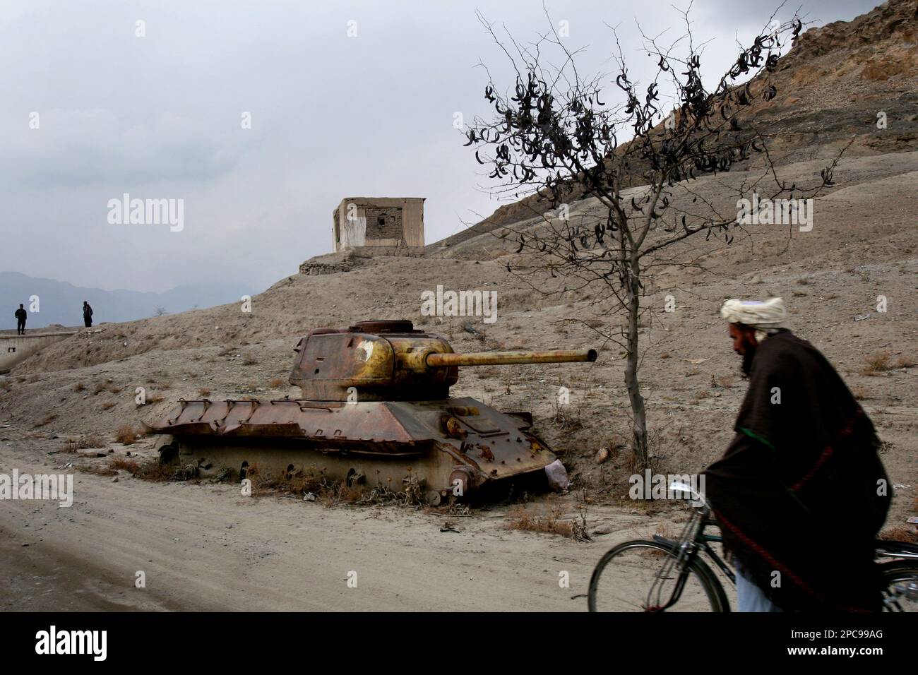 A man riding a bicycle passes next to an old destroyed Soviet tank used ...