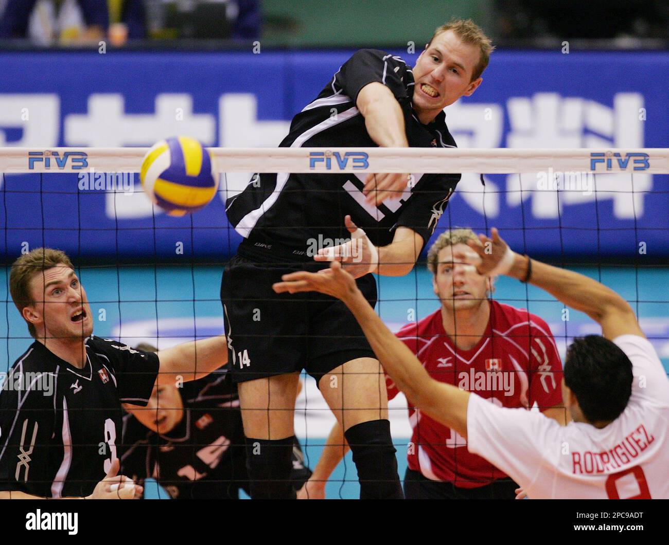 Canada's captain Murray Grapentine, center, spikes against Puerto Rico ...