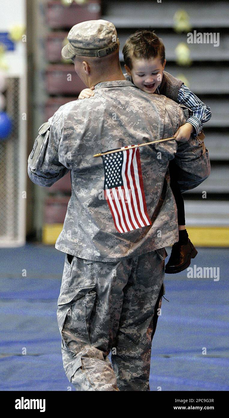 U.S. army Capt. Derrick Draper carries his son Joseph, 3, after he and ...