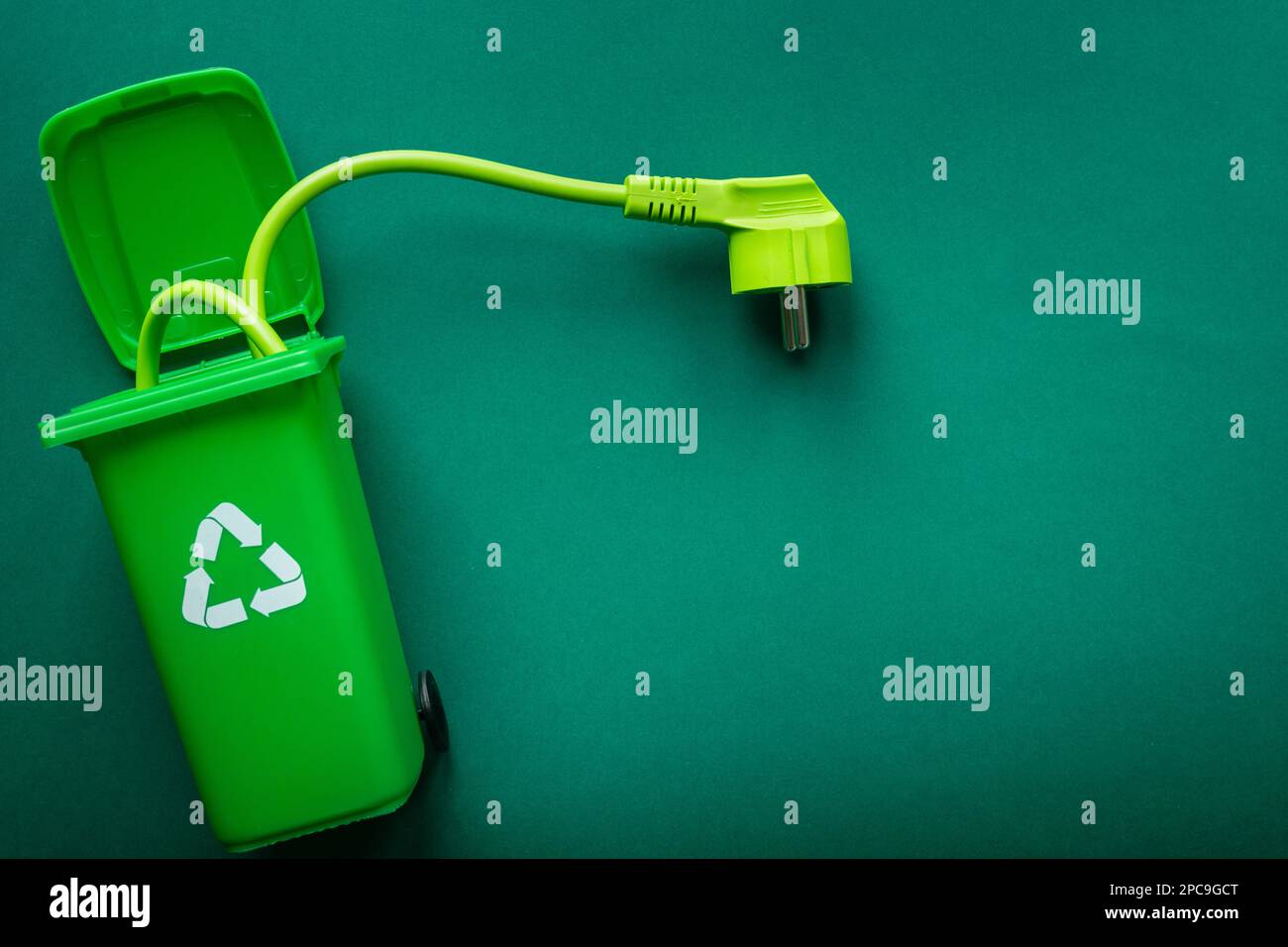 Green cable sticking out of a recycling bin, Environmental concept ...