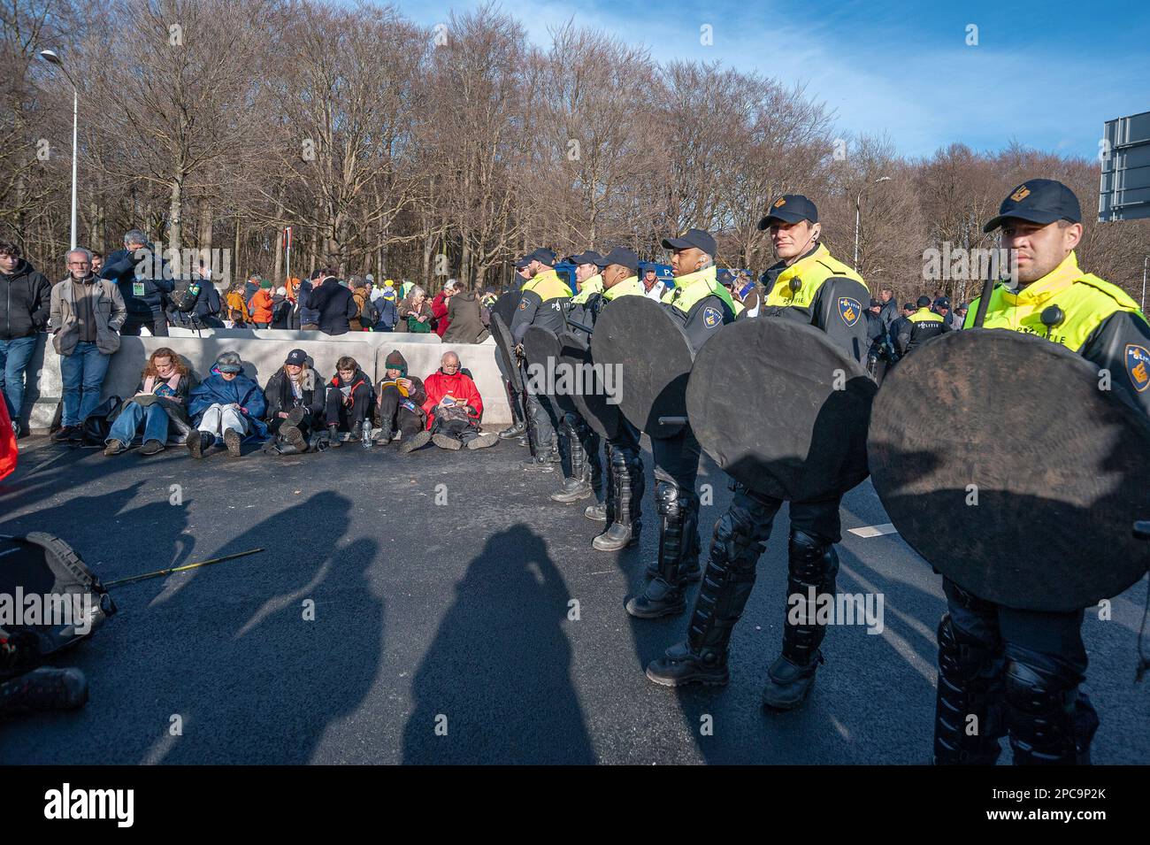 Policemen stand on guard as protesters sit-down during the ...