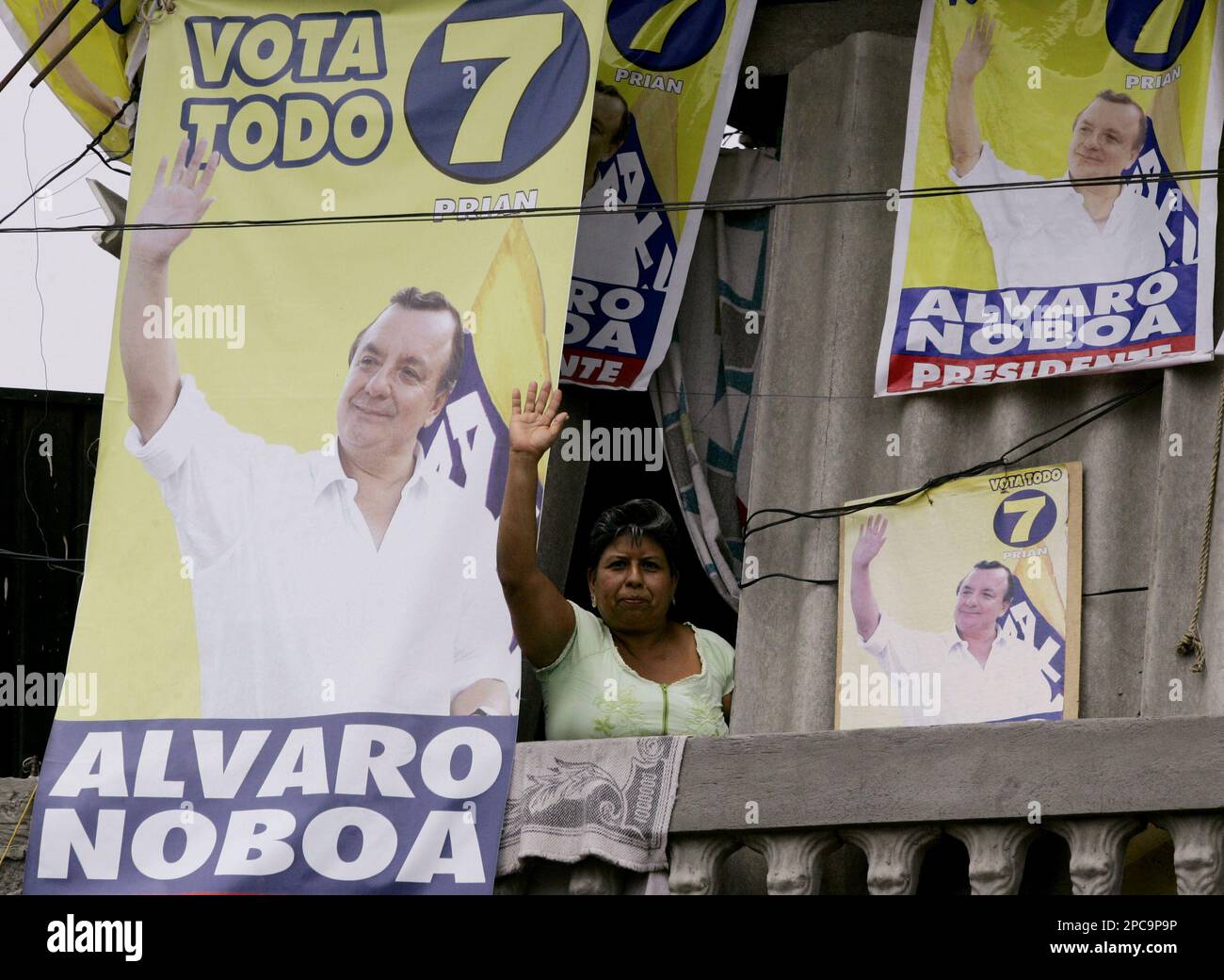 A woman waves beside an election posters of Ecuador's presidential candidate Alvaro Noboa in ...