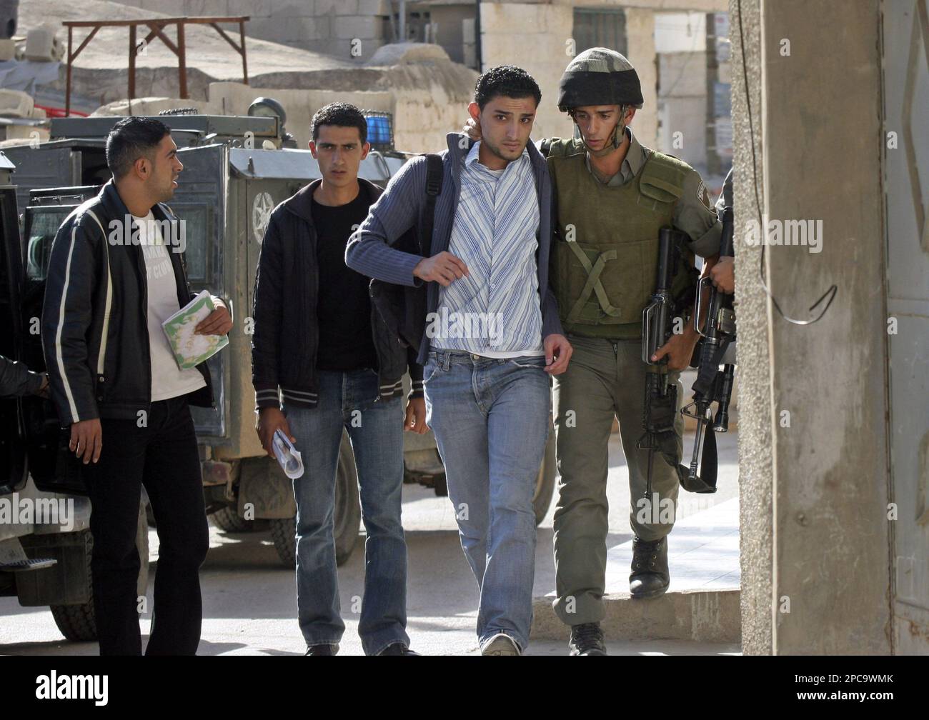 Israeli soldiers detain a Palestinian youth during an arrest raid in ...