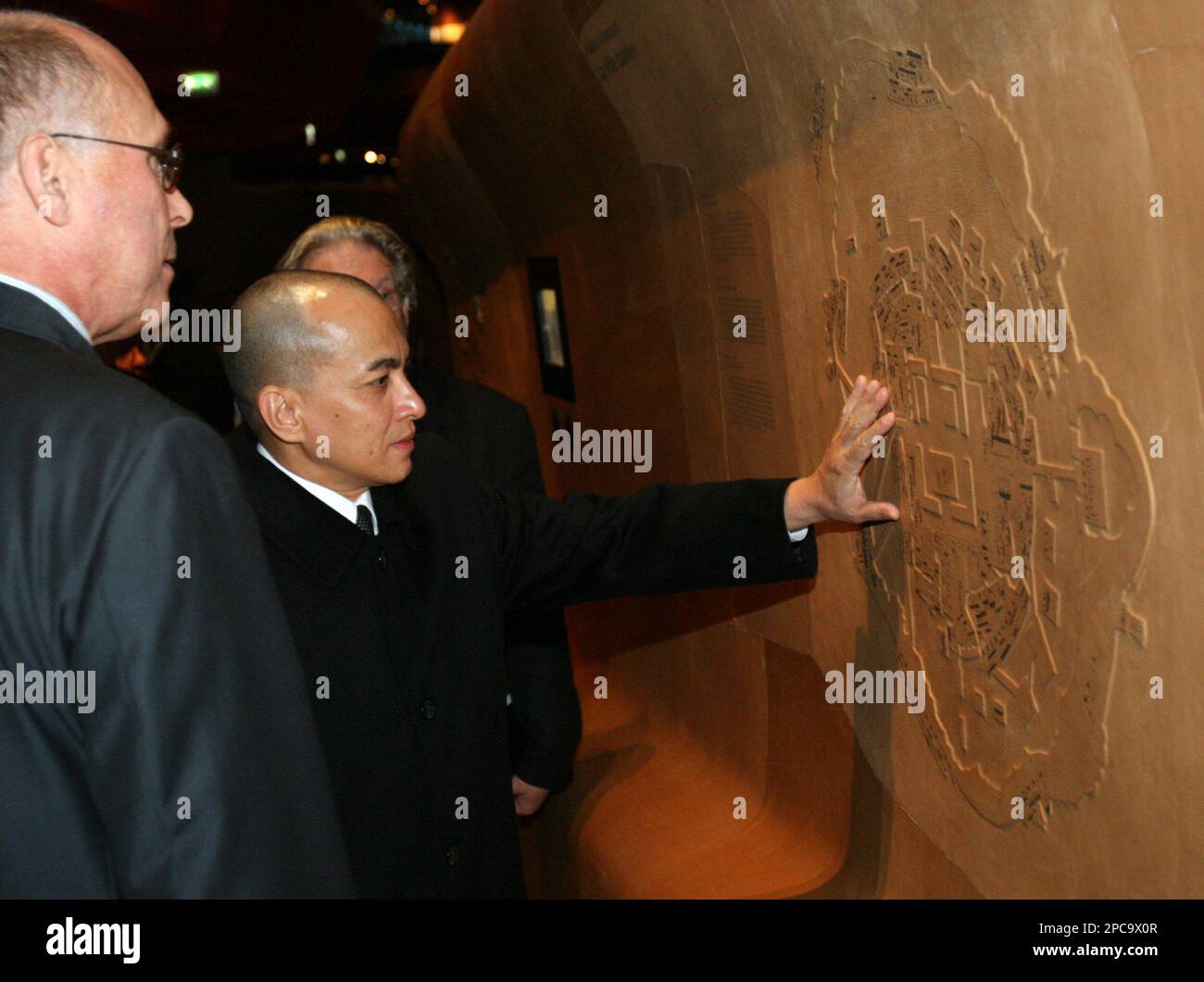 Cambodia's King Norodom Sihamoni touches a map as Quai Branly museum curator Stephane Martin ...