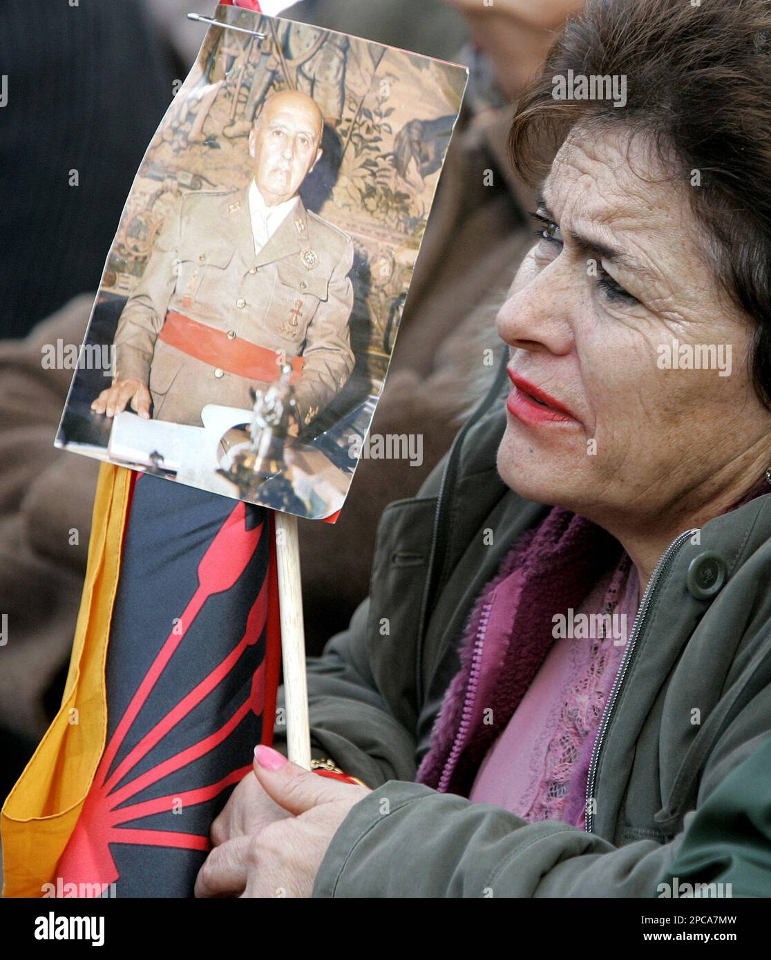 A woman holds a portrait of General Francisco Franco while listening to ...