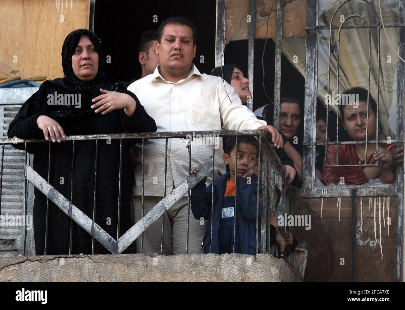 Residents observe the scene from their balcony following an explosion ...