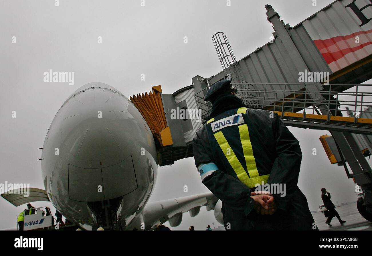 A man in uniform stands outside Airbus A380 on the tarmac at Narita ...