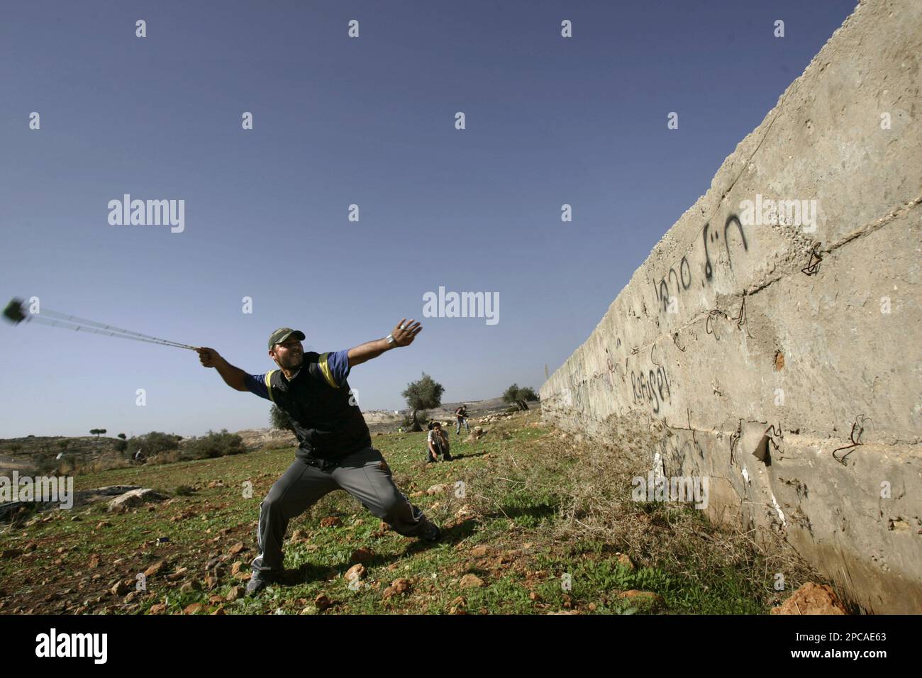 A Palestinian uses a slingshot to throw a stone at Israeli border ...