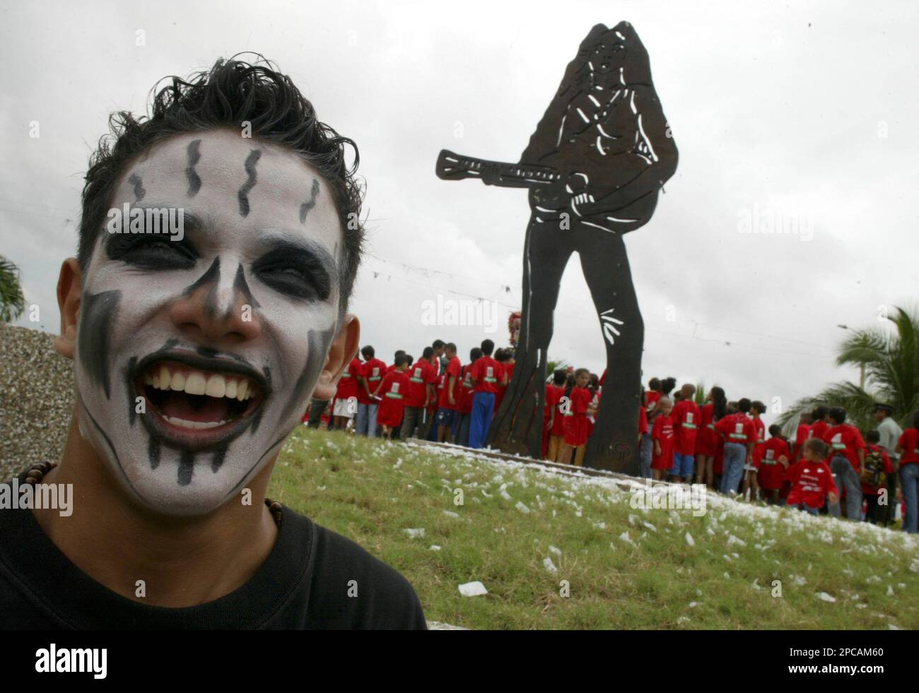 A fan of pop singer Shakira laughs in front of a statue of her in front ...