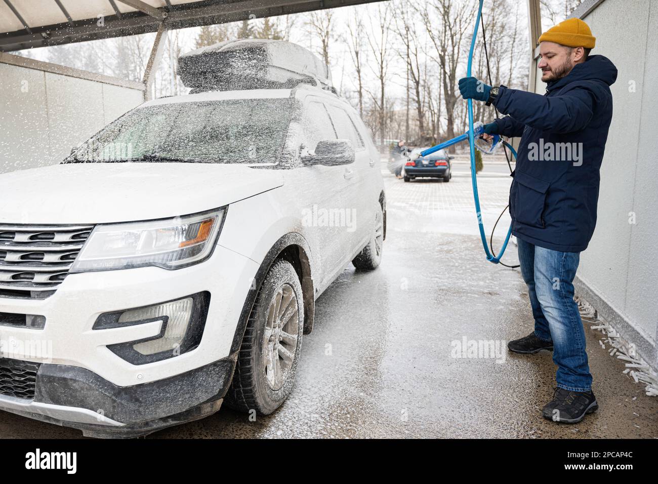 Man washing american SUV car with roof rack at a self service wash in ...