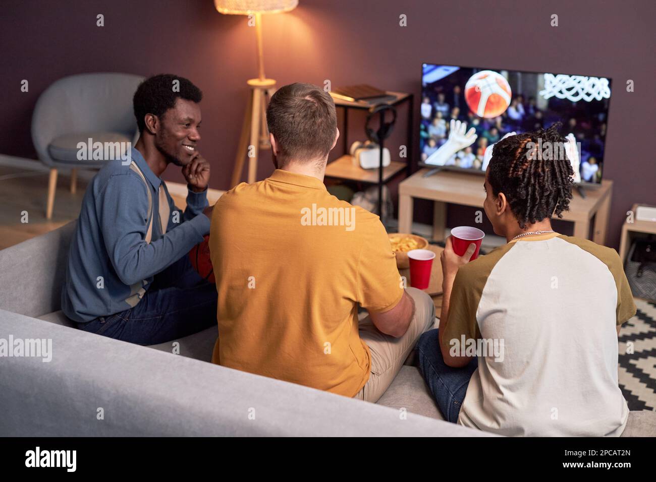 Back view at group of sports fans watching basketball match at home on ...
