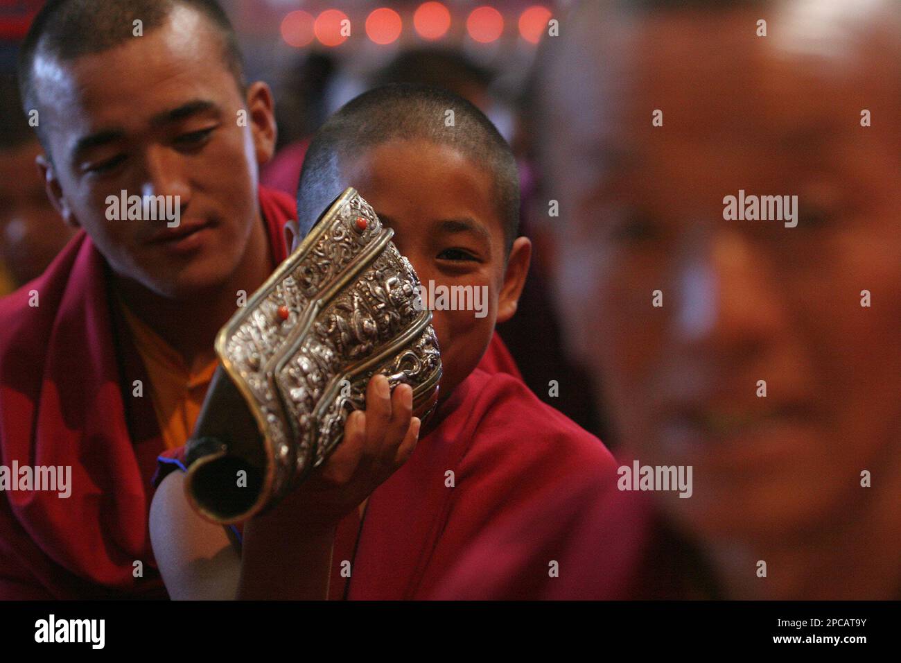 A young buddhist monk holds a traditional musical instrument during a ...