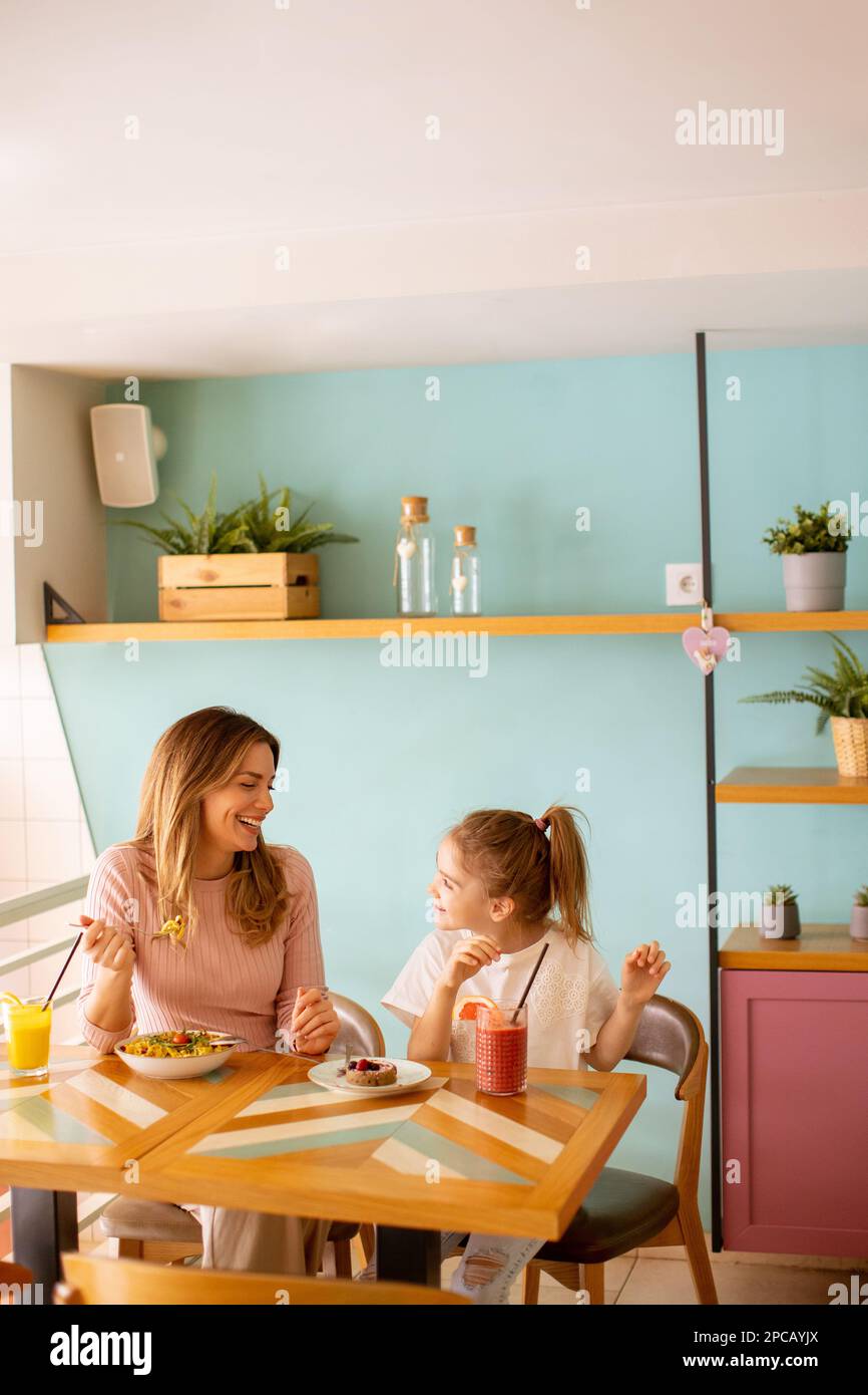 Mother and daughter having good time during breakfast with fresh ...