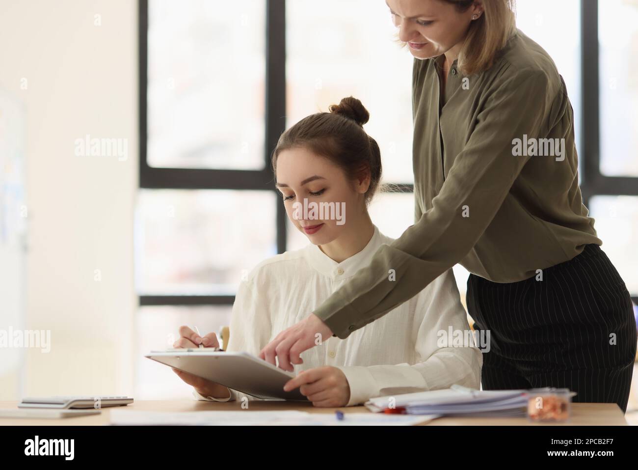 Boss woman pointing at documents while standing near her young manager ...