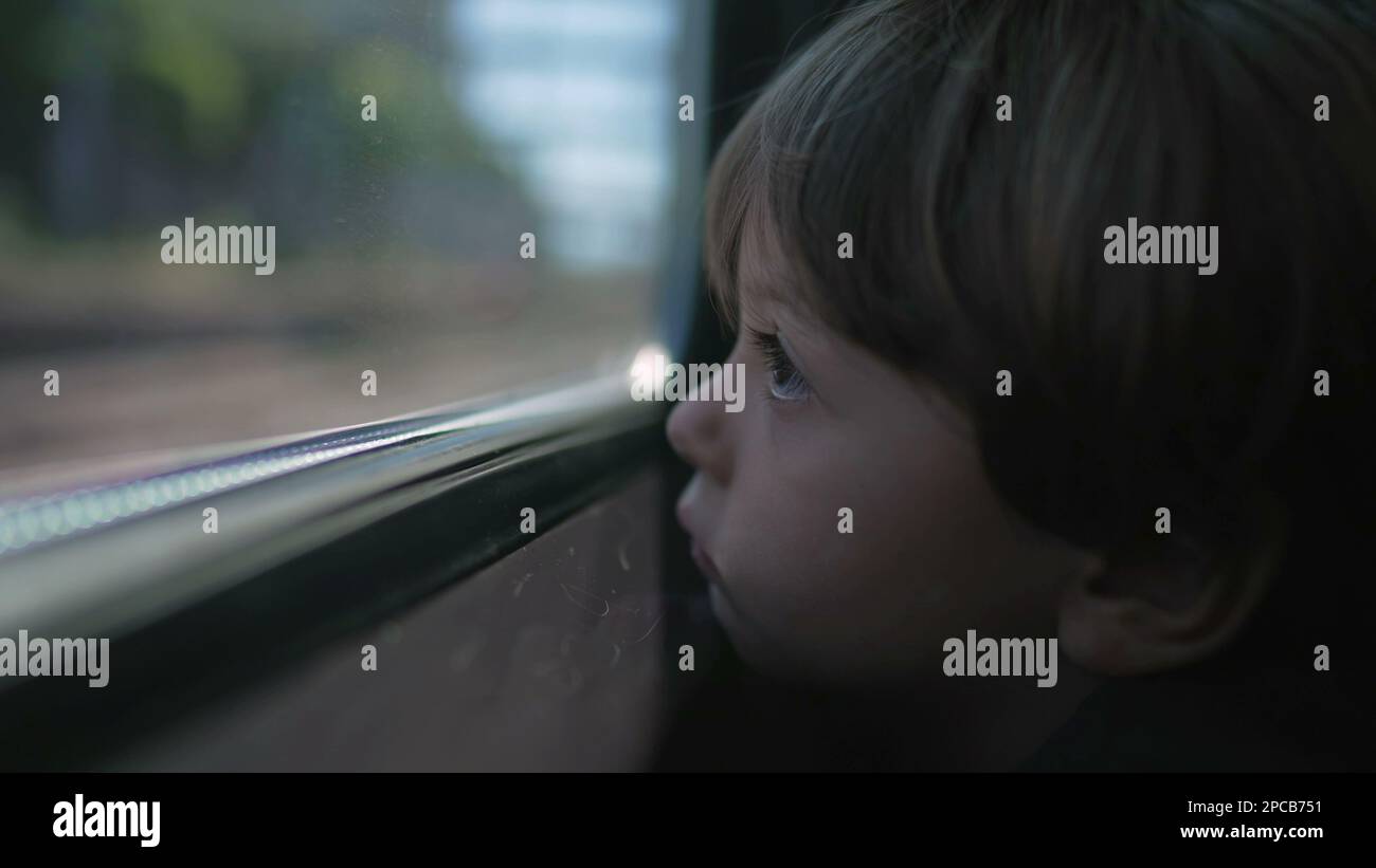 One sad little boy leaning on train window. Close up face of ...