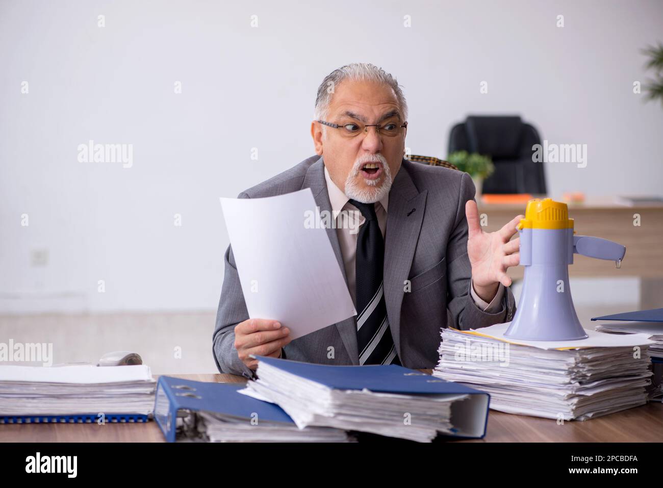 Old male boss holding megaphone at workplace Stock Photo - Alamy