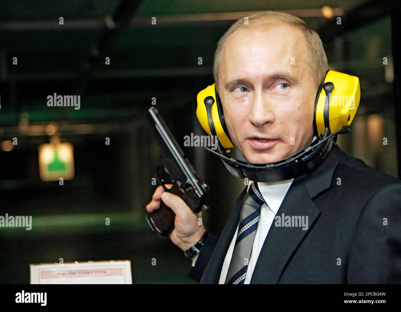 President Vladimir Putin wears headphones as he tests a pistol in a ...