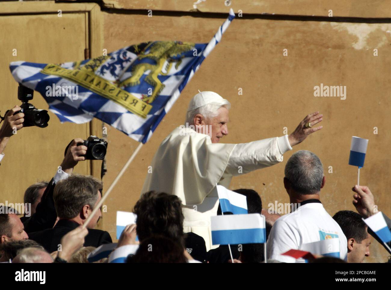 Pope Benedict XVI waves as he is driven through the crowd, waving a ...