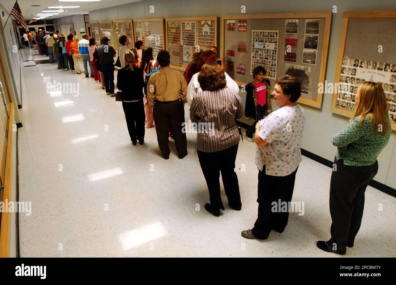 Voters wait in a long line to cast their ballots in a long hallway ...