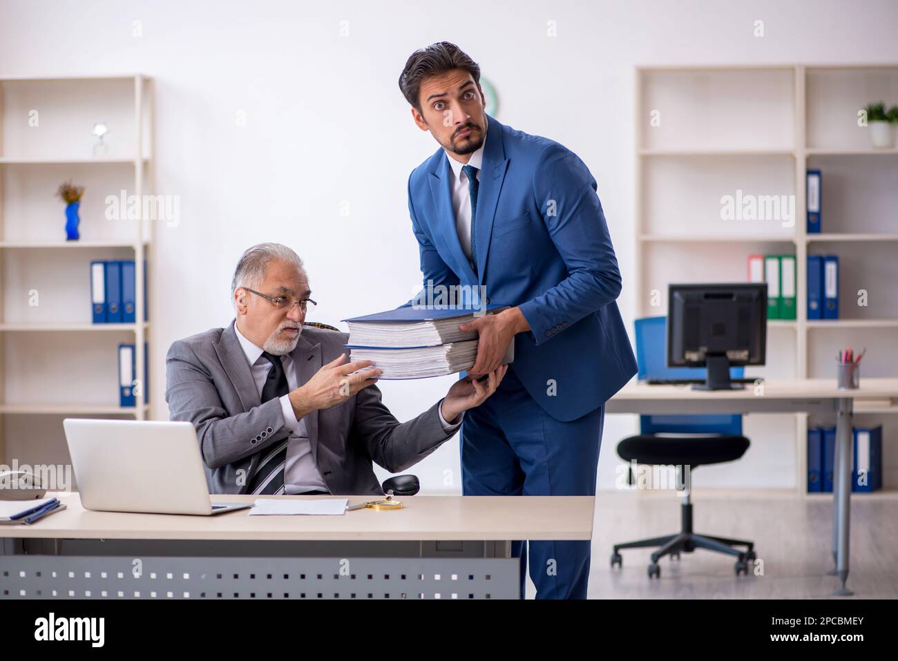 Old boss and young employee working at workplace Stock Photo - Alamy