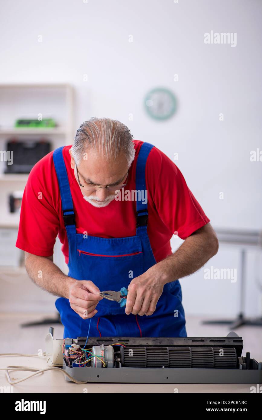 Old male repairman repairing air-conditioner Stock Photo - Alamy