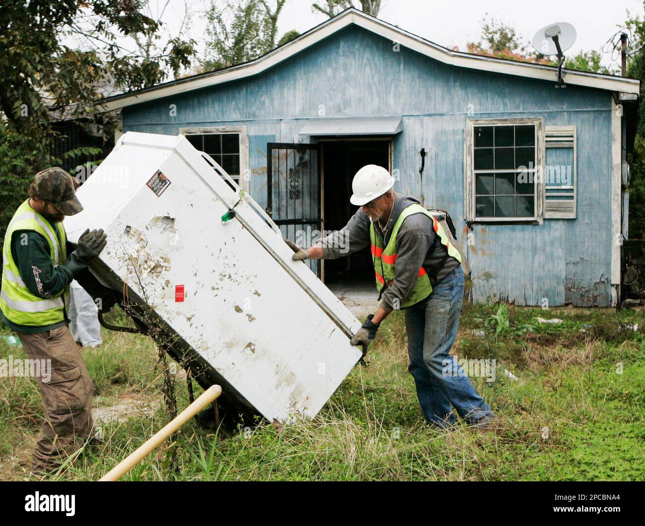 FEMA contractors remove a refrigerator from the front of a gutted home ...